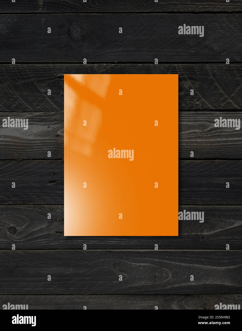 Orange booklet cover isolated on black wood background, mockup template ...