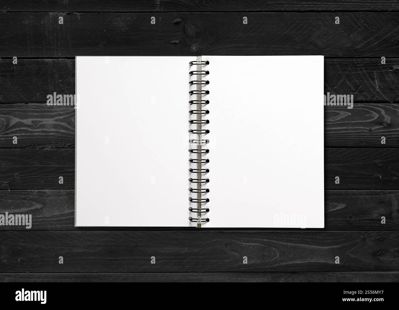 Blank open spiral notebook mockup isolated on black wood background ...
