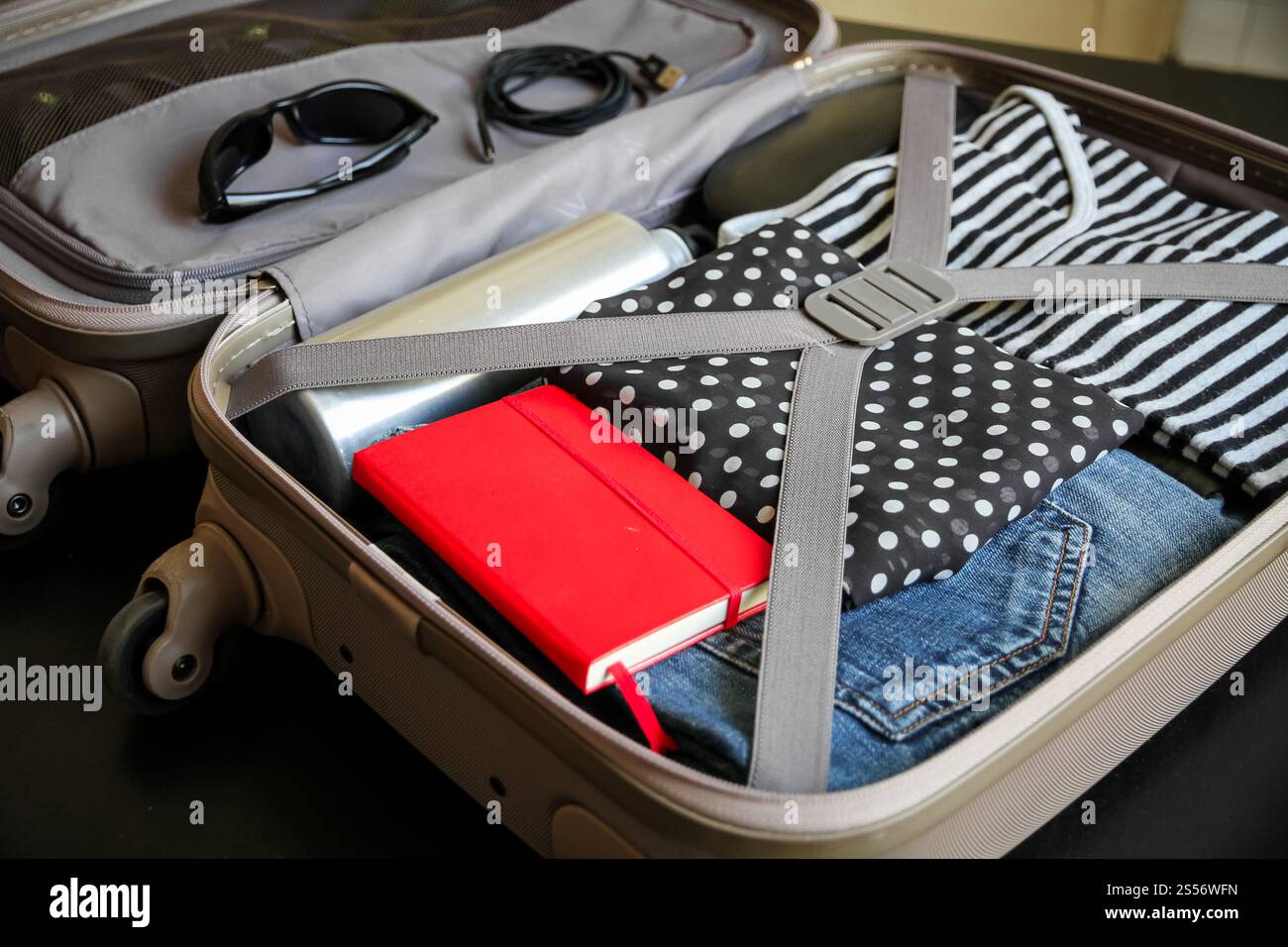 Open travel suitcase full of clothes isolated on black background. Open ...