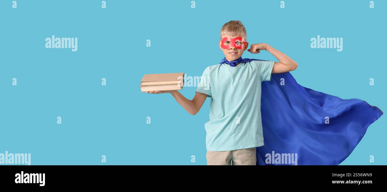 Little boy dressed as superhero holding books and showing muscles on ...