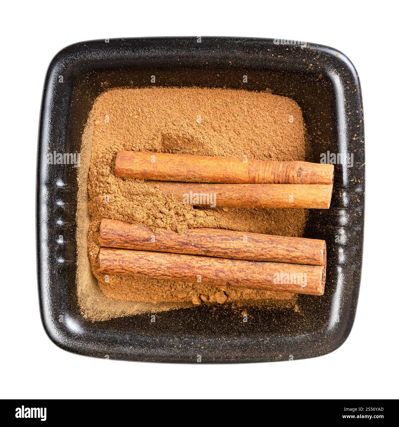 top view of cinnamon sticks and powder in black bowl isolated on white ...