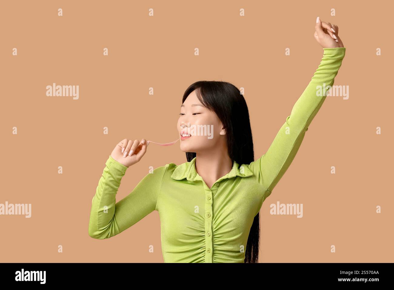 Pretty young Asian woman pulling chewing gum on beige background Stock ...