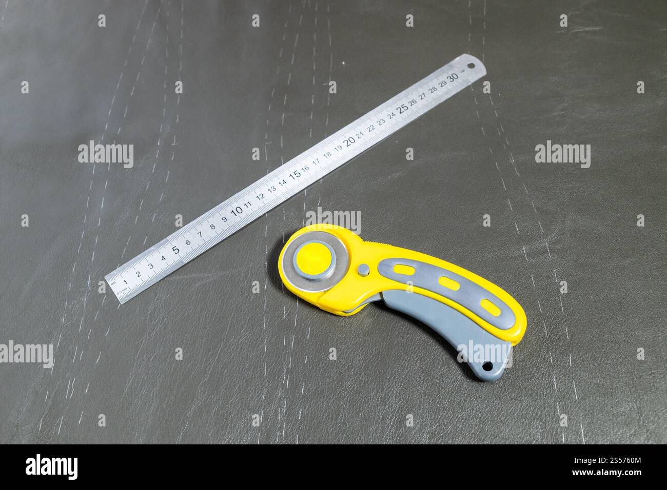 steel ruler and rotary cutter on surface of leather with drawn pattern ...
