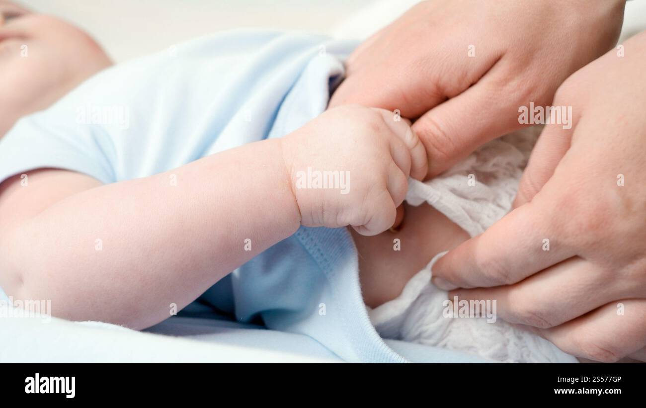 Closeup of mother taking off and changing messy diapers of her little ...