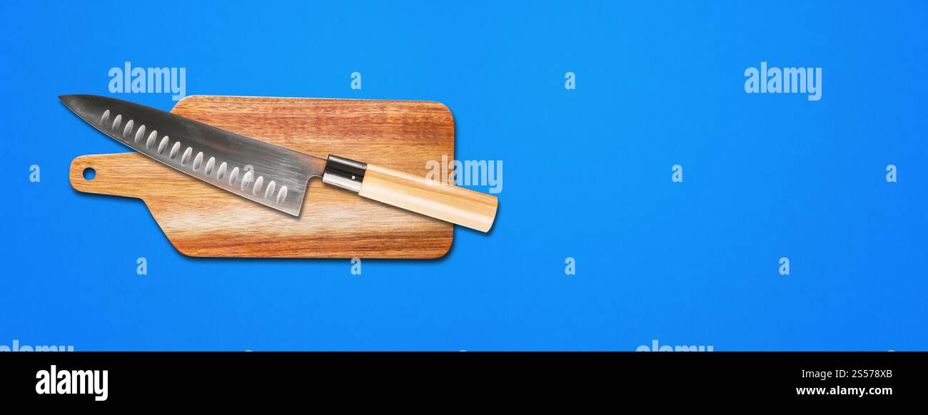 Traditional Japanese gyuto chief knife on a cutting board. Blue banner ...
