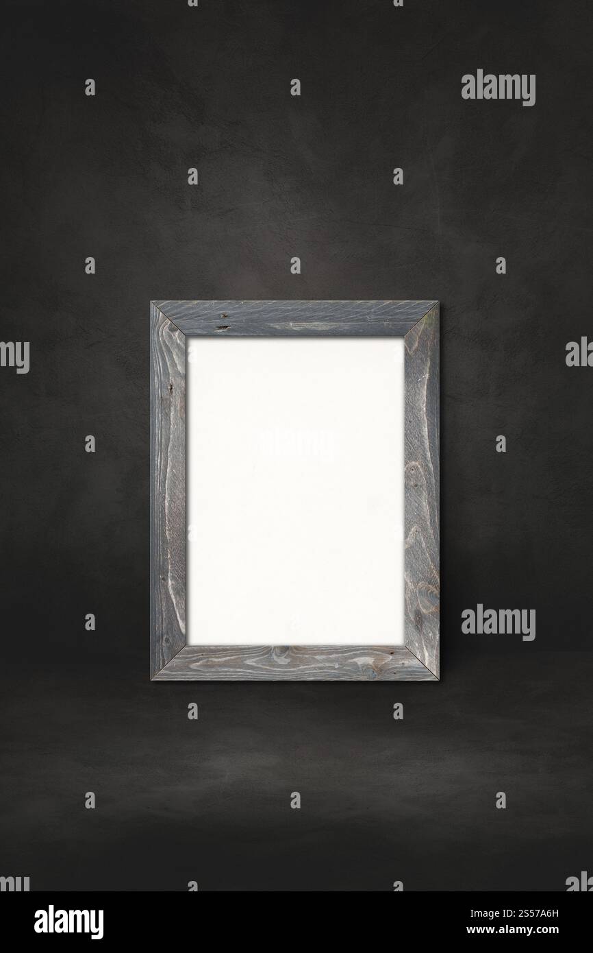 Wooden picture frame leaning on a black wall. Presentation mockup ...