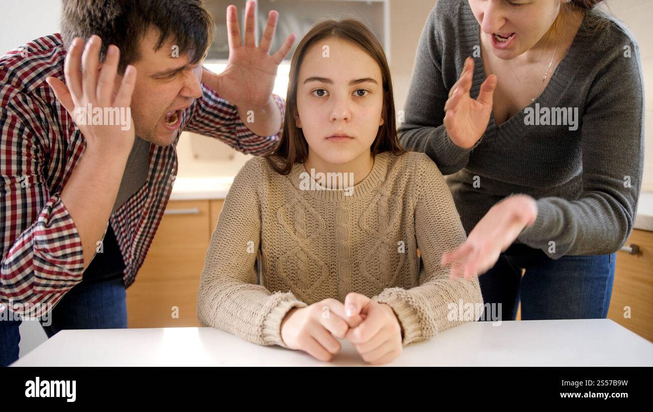 Father and mother shouting and screaming at teenage daughter sitting ...