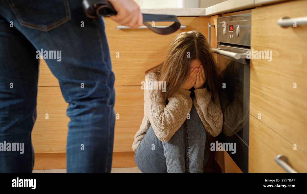 Angry father holding leather belt and threats crying daughter sitting ...