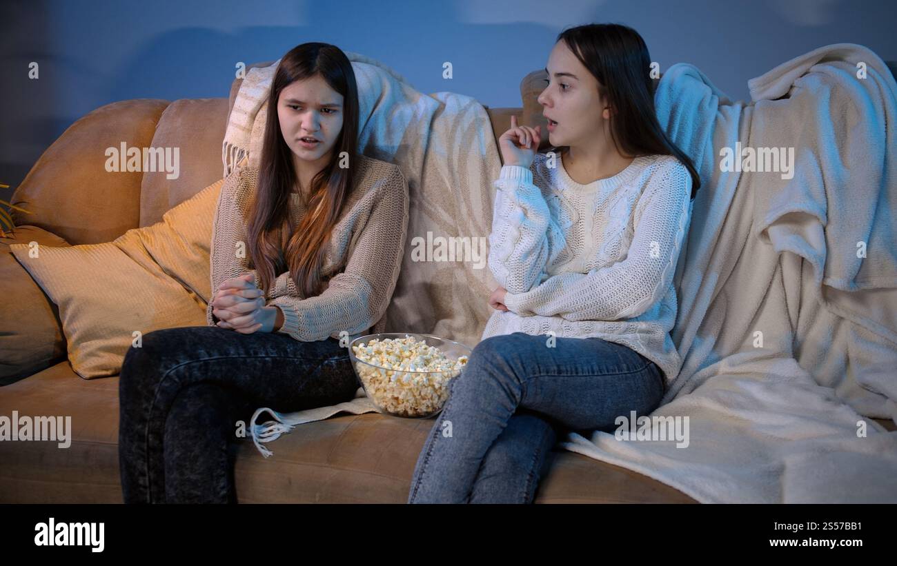 Two girls watching movie on TV and talking at night. Two girls watching ...