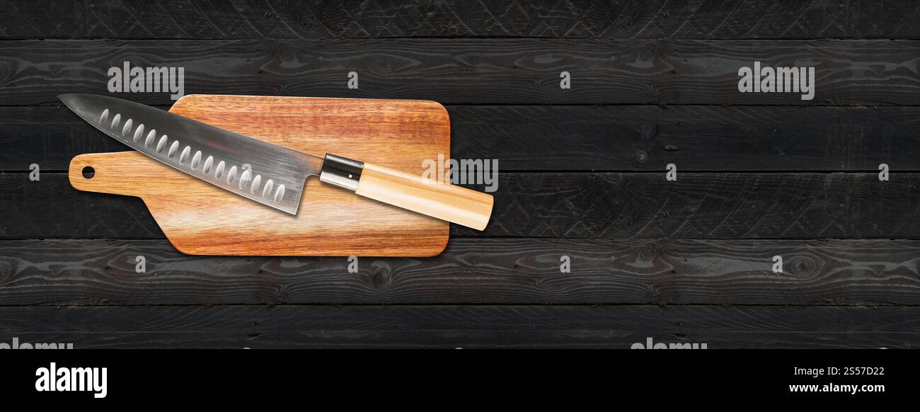 Traditional Japanese gyuto chief knife on a cutting board. Black wooden ...