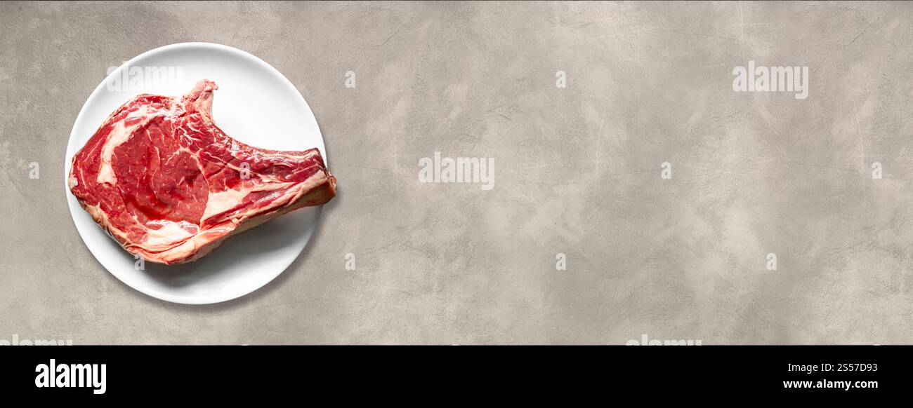 Raw beef prime rib and plate isolated on light concrete background. Top ...