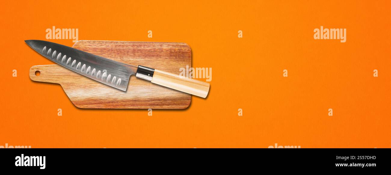 Traditional Japanese gyuto chief knife on a cutting board. Orange ...