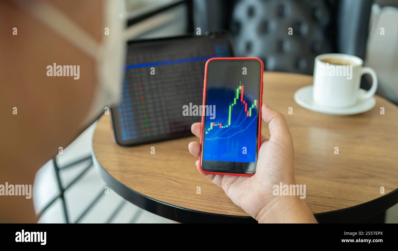 Investor holding phone and looking at candlestick chart suitable for ...