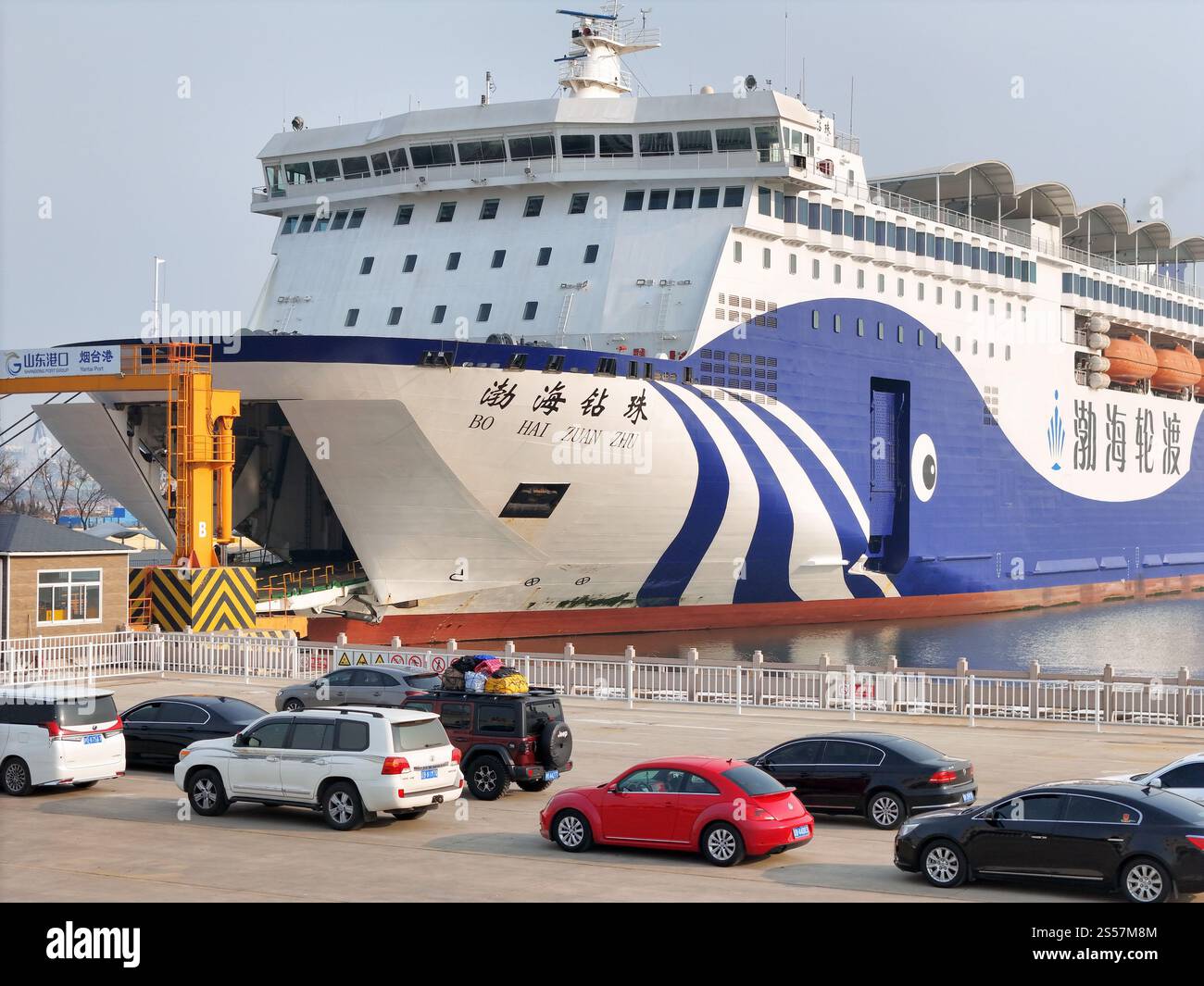 Vehicles prepare to enter a passenger roller ship for Dalian at the ...
