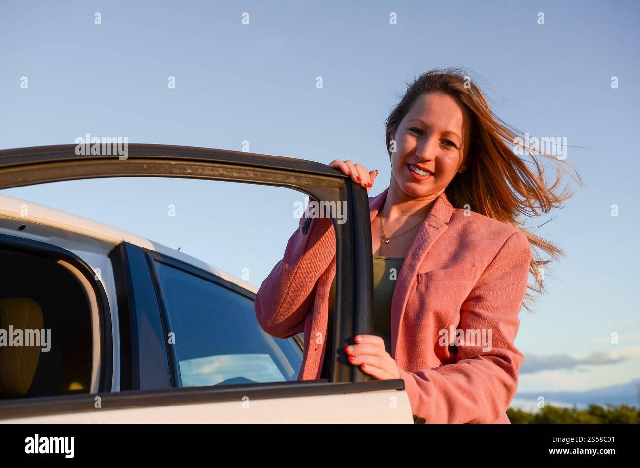 Smiling businesswoman getting out of her car during a road trip at ...