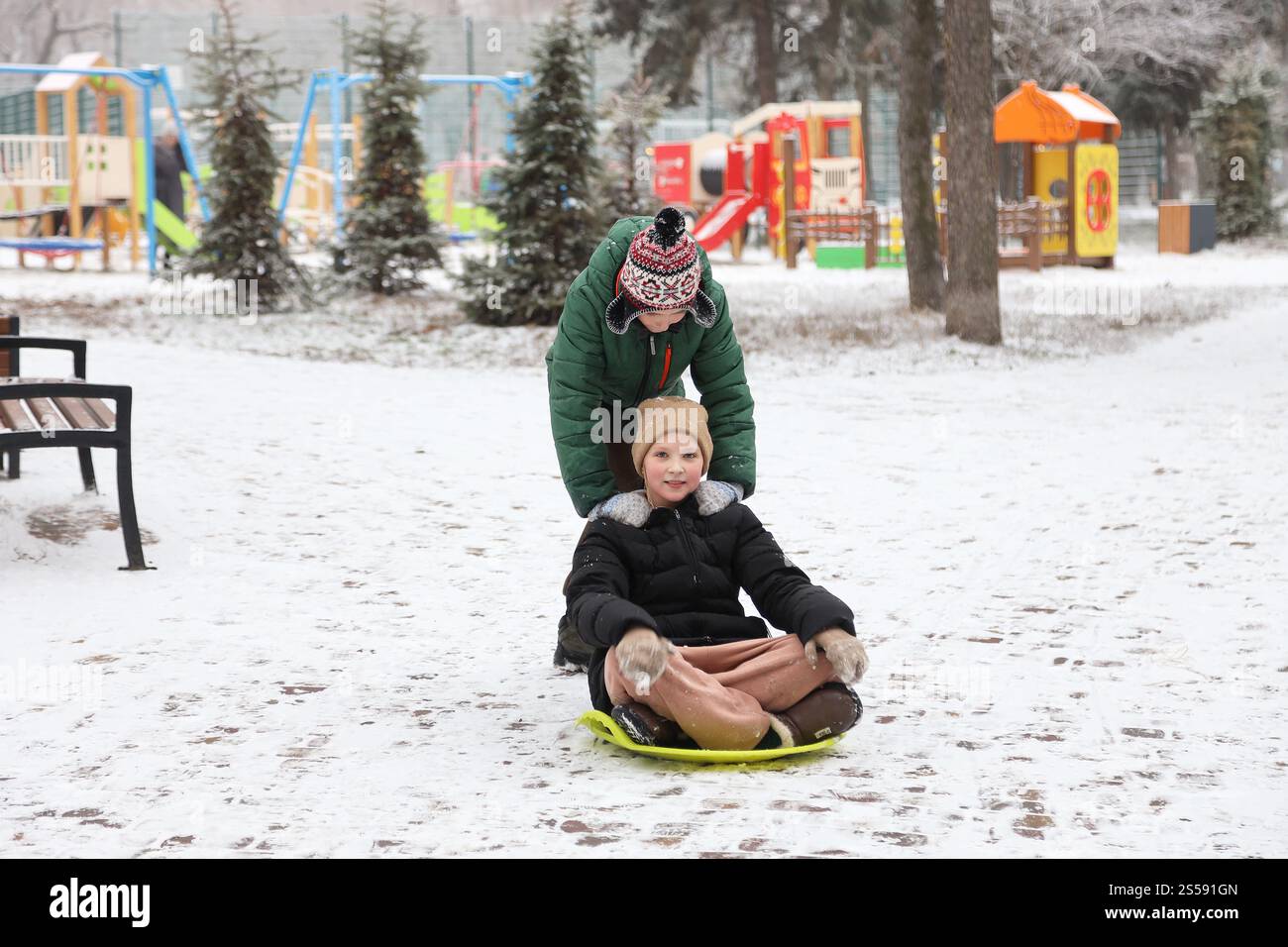 Children are walking, hiking,, sledding and playing in a snowy park ...