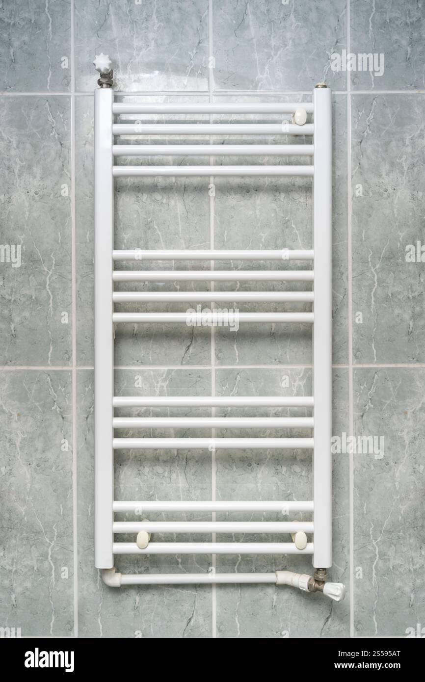 White radiator hung on the wall in a bathroom with green ceramic tiles ...