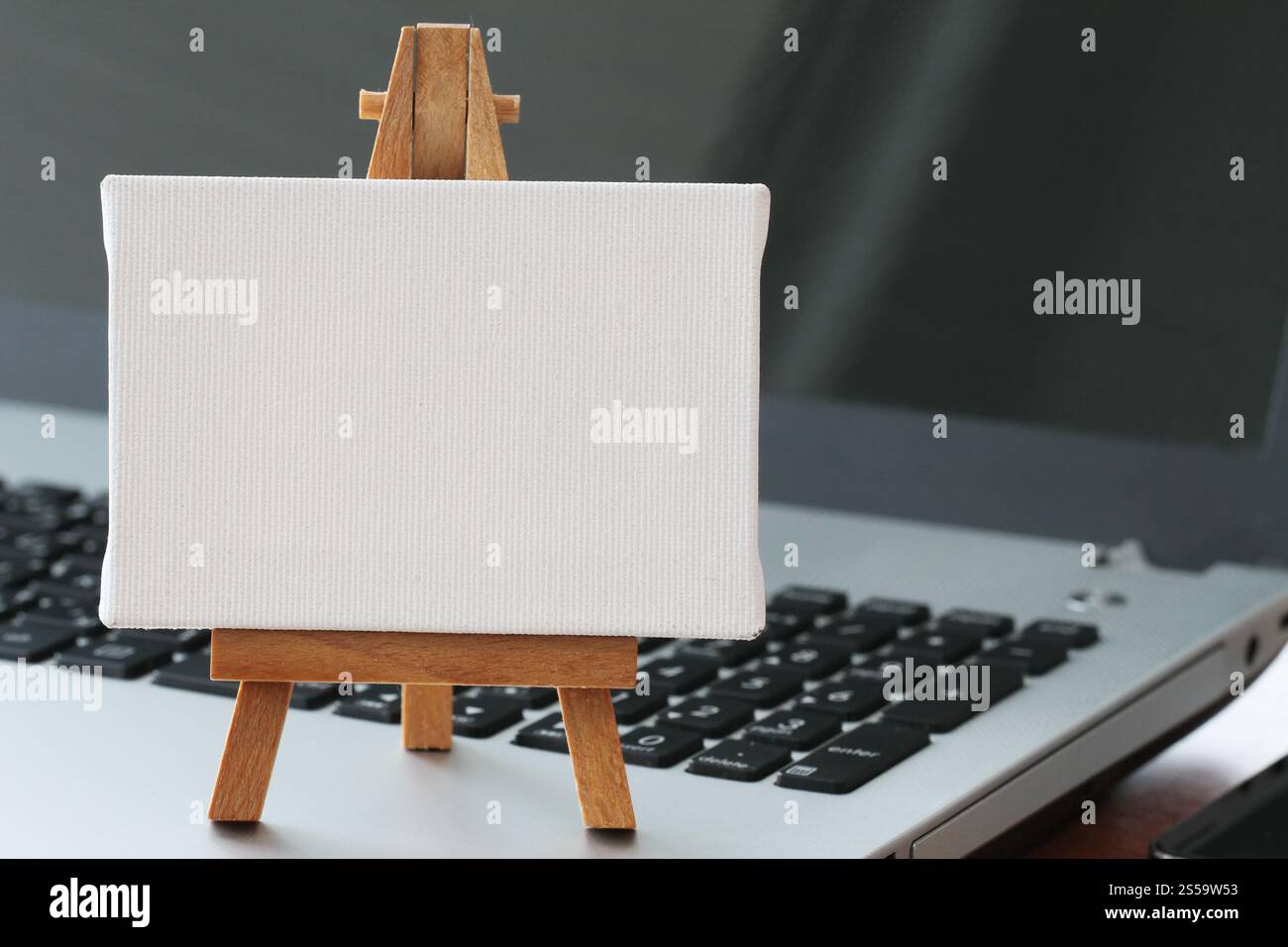 blank canvas and wooden easel on laptop computer as concept Stock Photo ...
