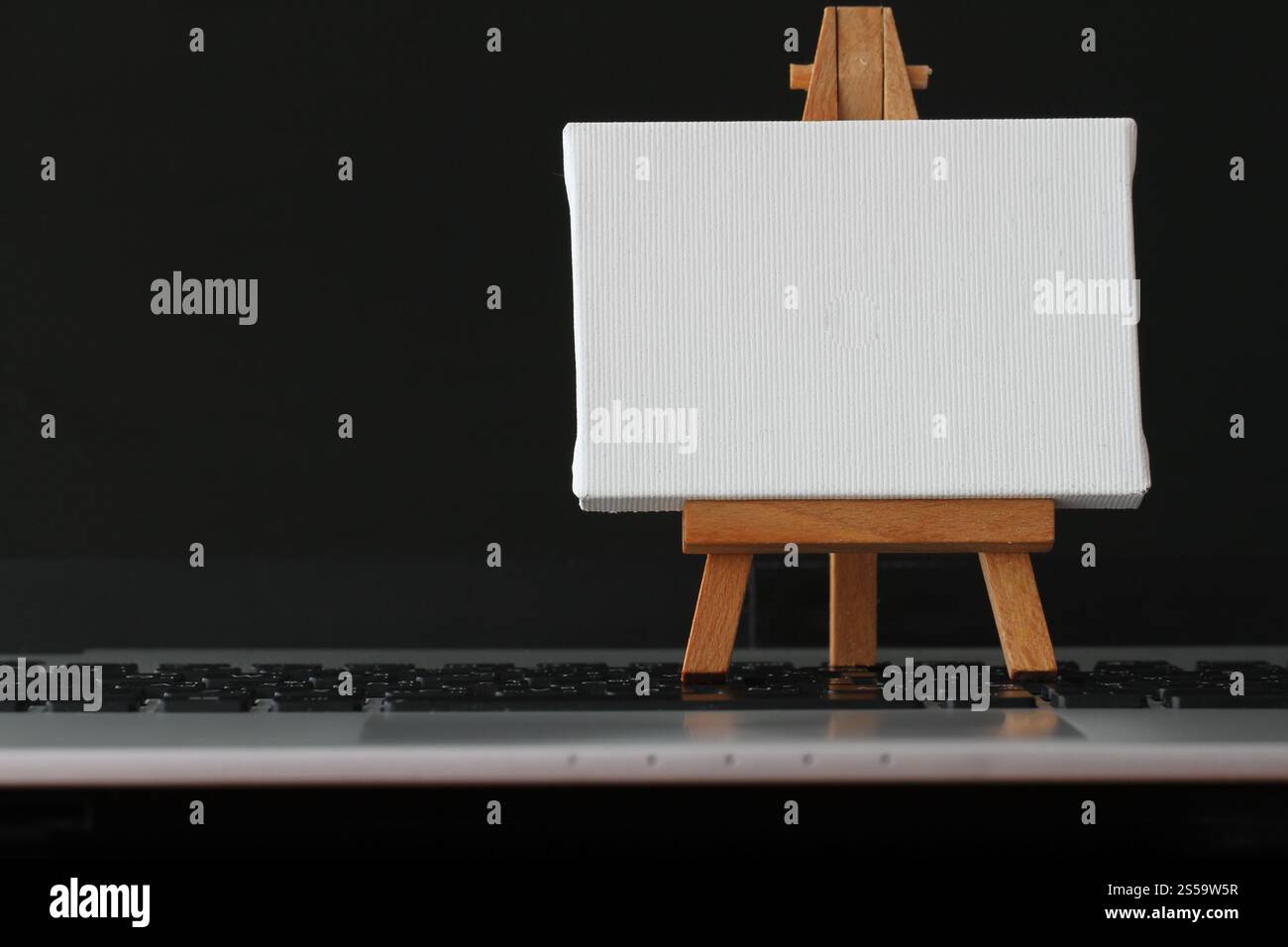 blank canvas and wooden easel on laptop computer as concept Stock Photo ...