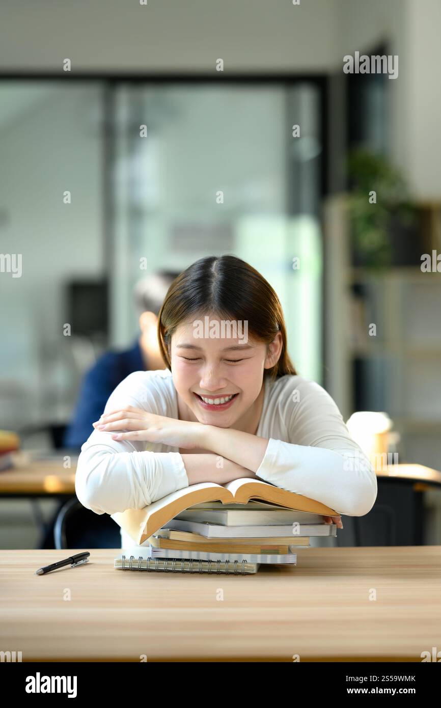 Smiling young woman taking a break during study time resting her head ...