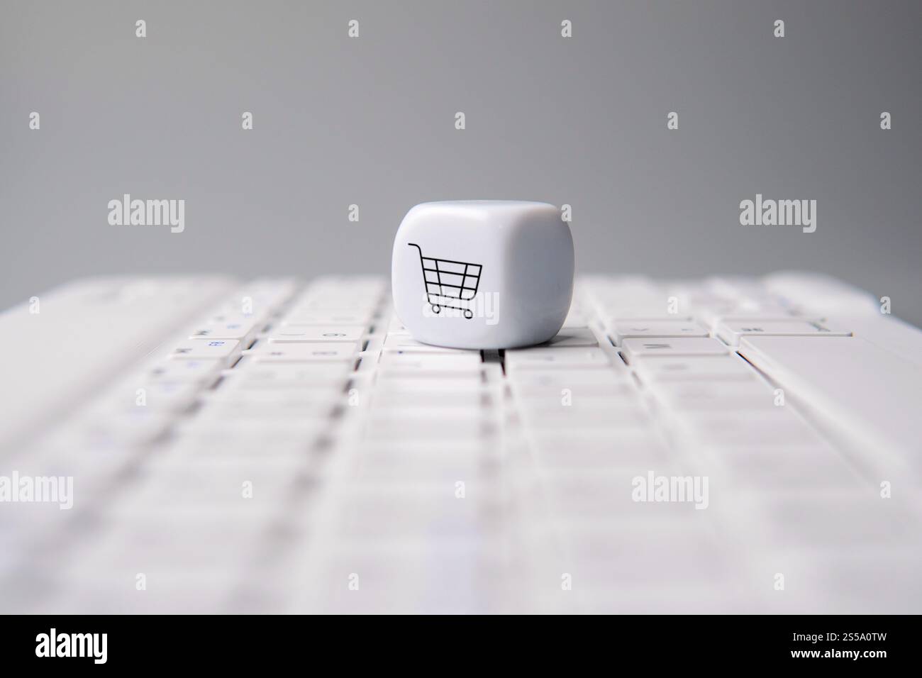 A white die with a shopping cart symbol on a laptop keyboard. Online ...