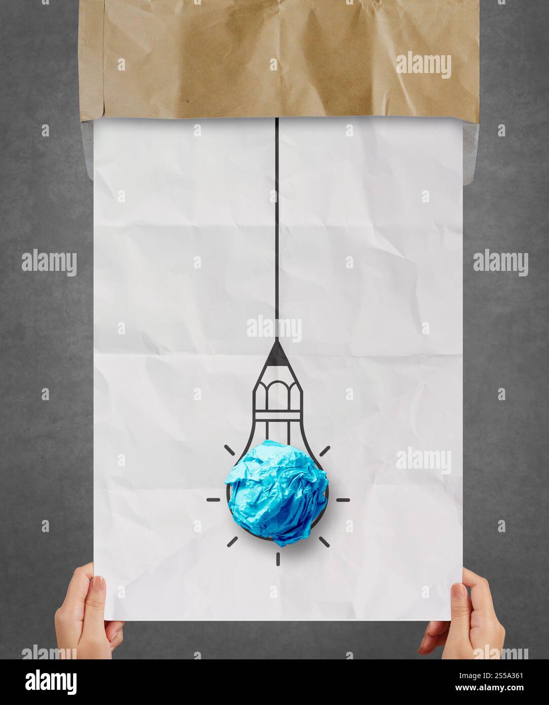 hand pulling light bulb crumpled paper out of recycle envelope as ...