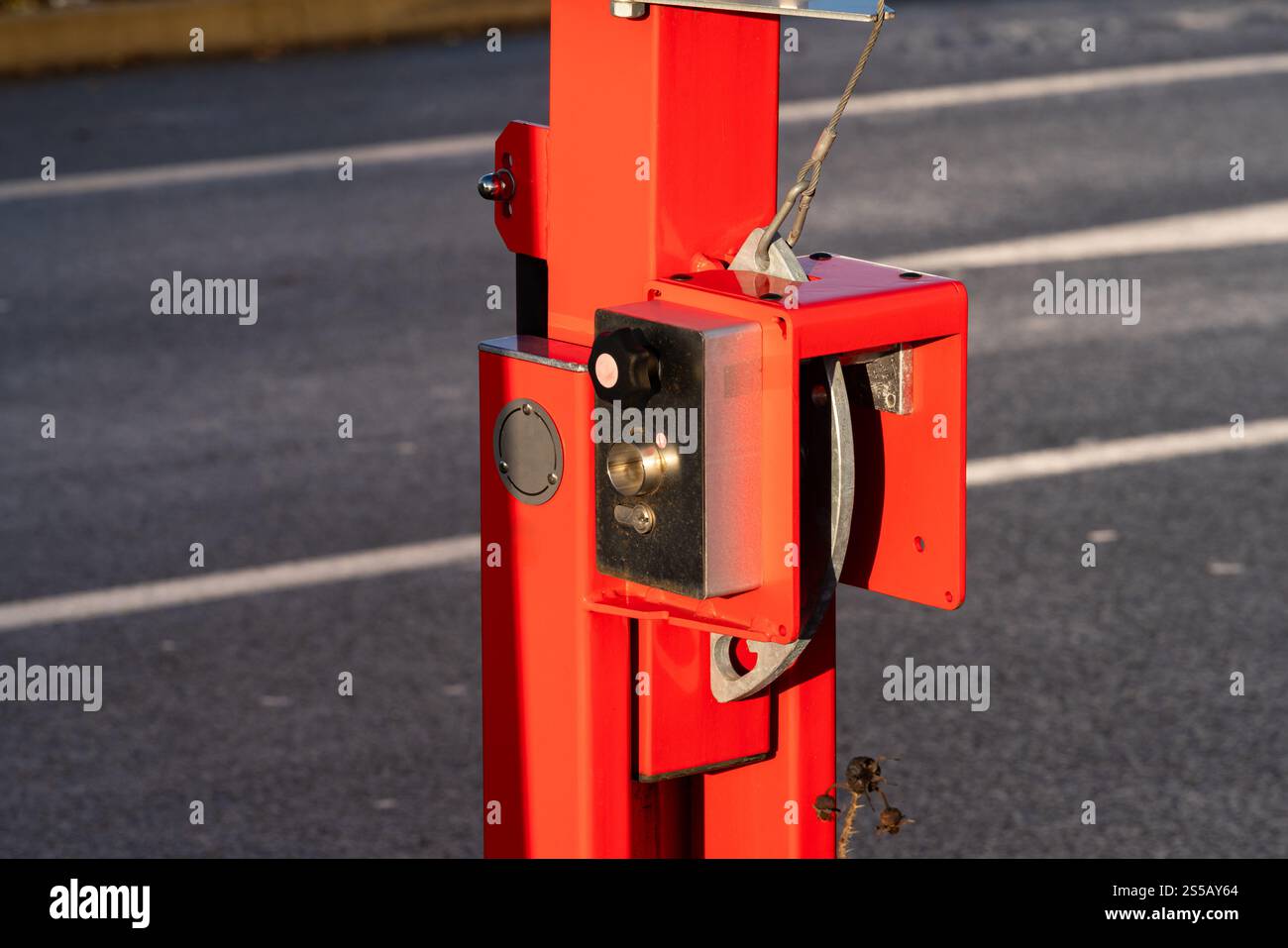 A bright red gate mechanism is affixed to a sturdy post, resting on a ...