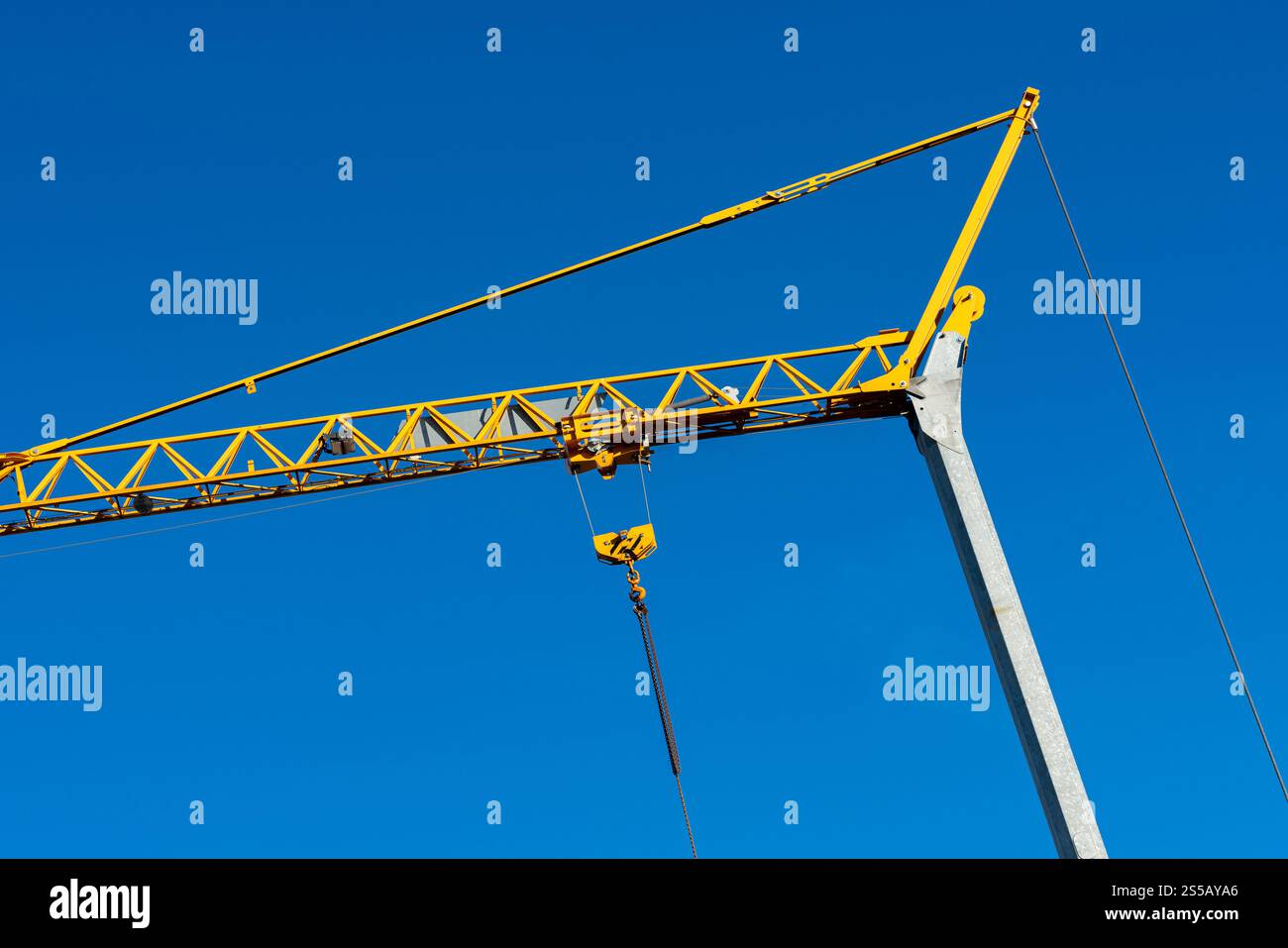 A tall construction crane reaches high above a clear blue sky ...