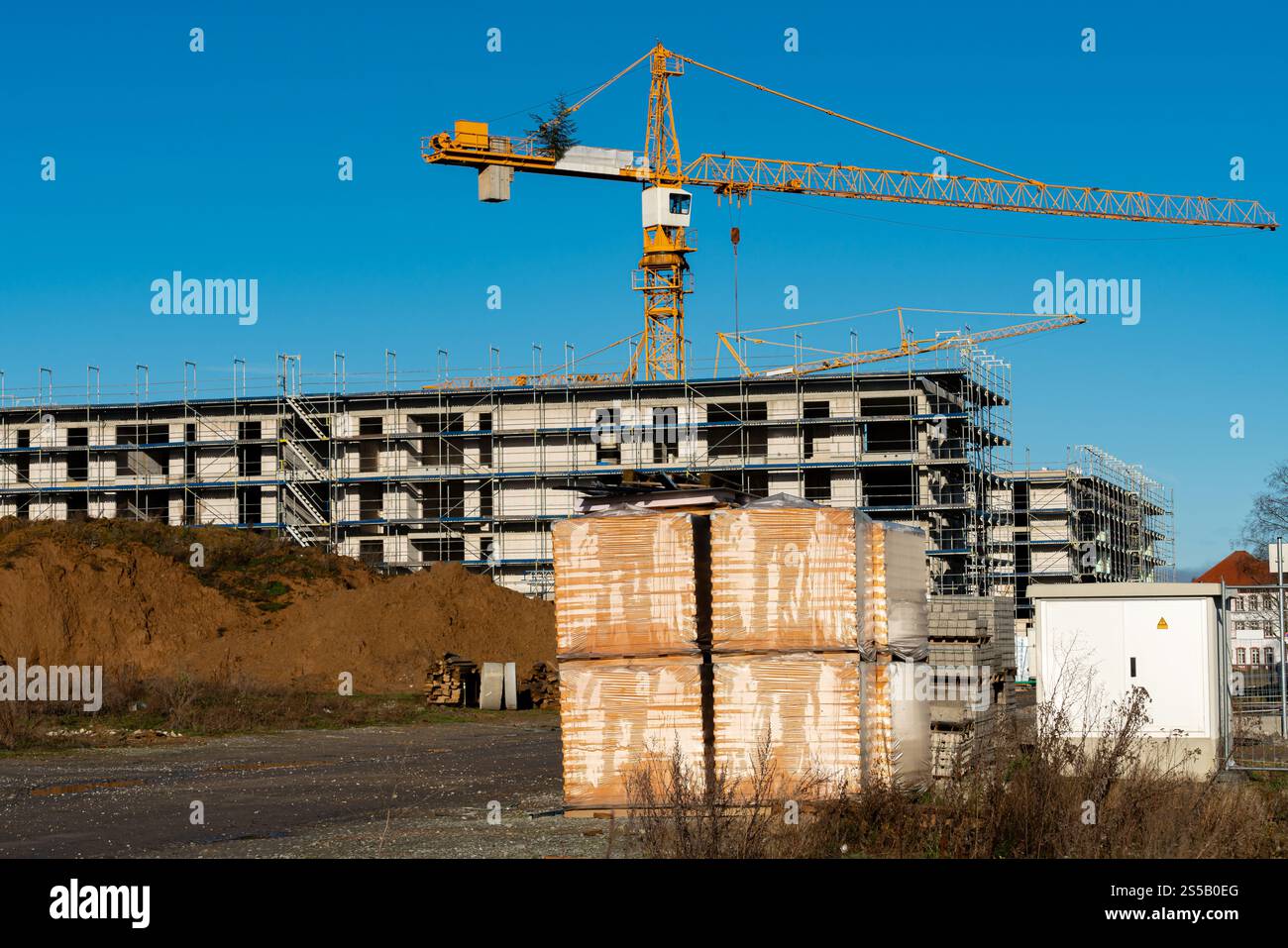 A construction site features a large crane towering over a multi-story building under ...