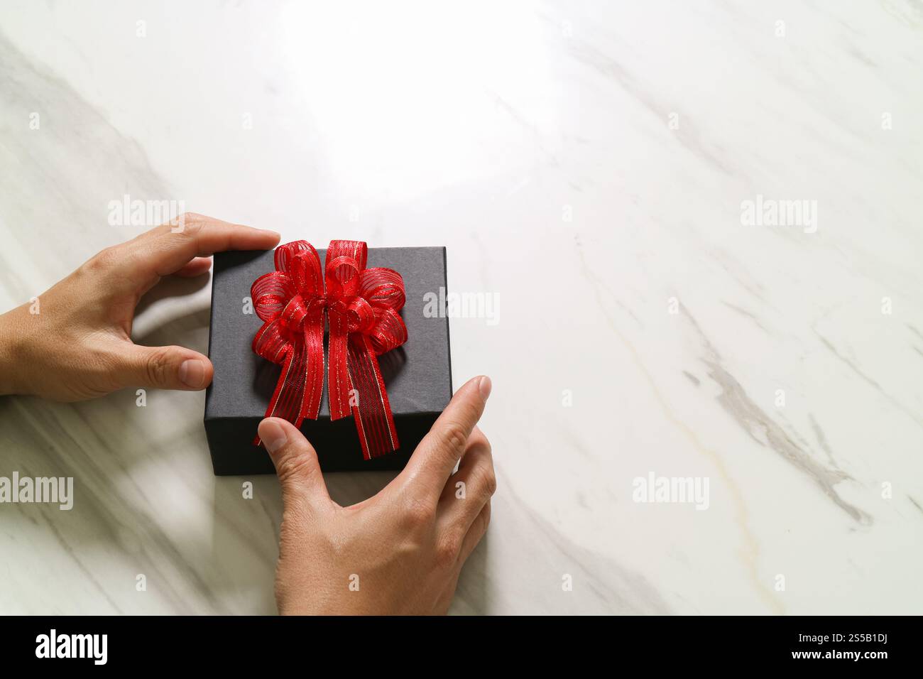 gift giving,man hand holding a gift box in a gesture of giving on white gray marble table ...