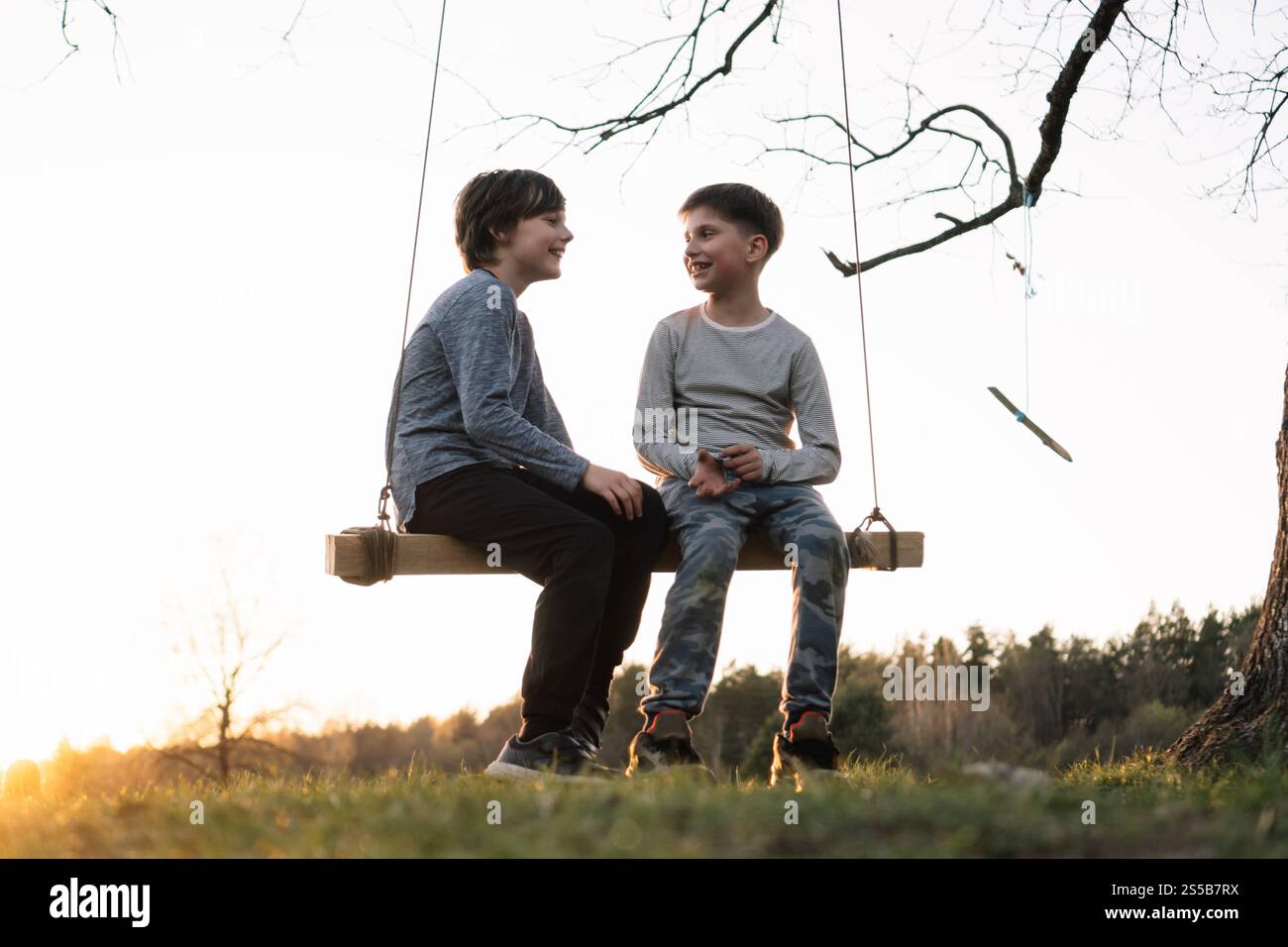 Friendship. Two teenagers, friends are sitting on swing against gray ...