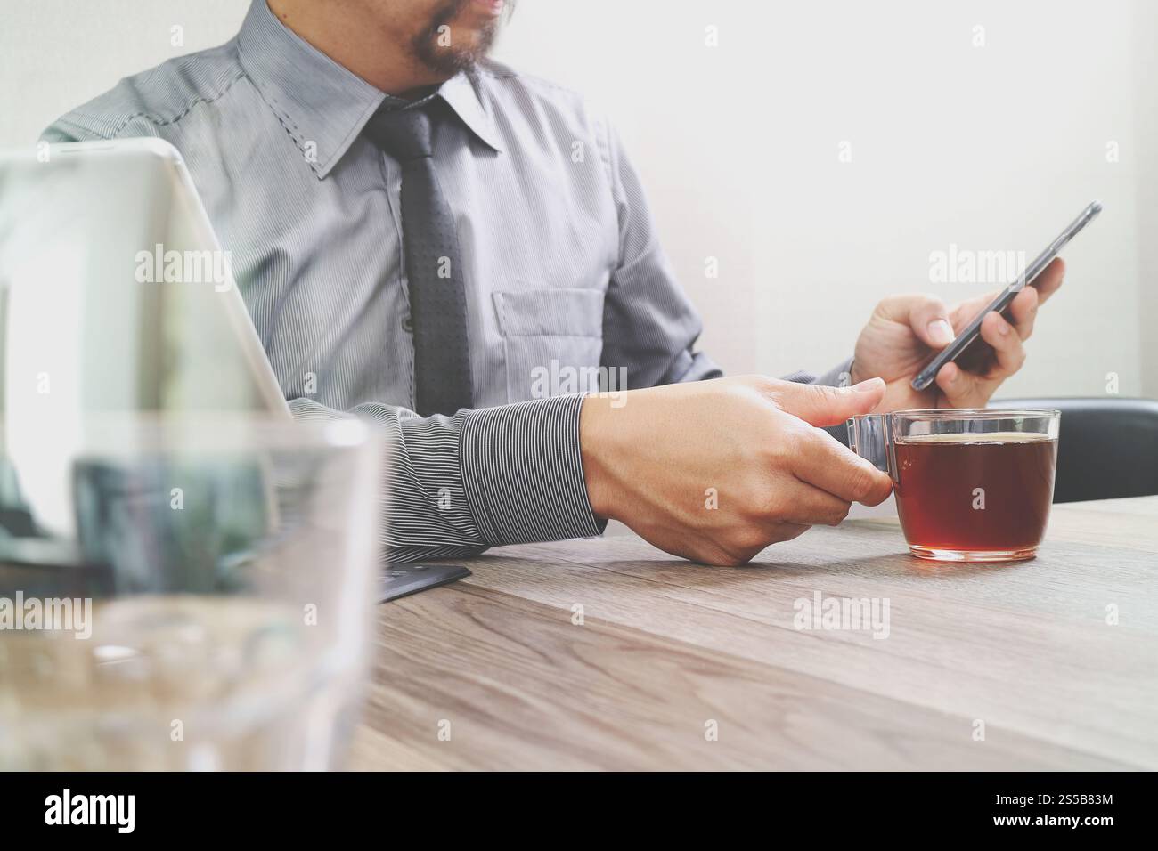 success businessman hand using smart phone,digital tablet docking smart keyboard,coffee cup on ...