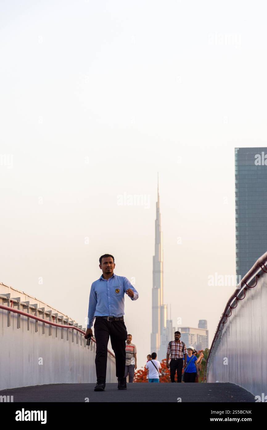 A person walking on a bridge with the iconic Burj Khalifa towering in ...