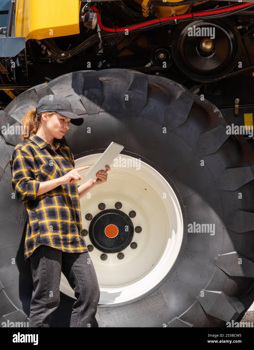 Female agricultural farmer standing next to a combine harvester and ...