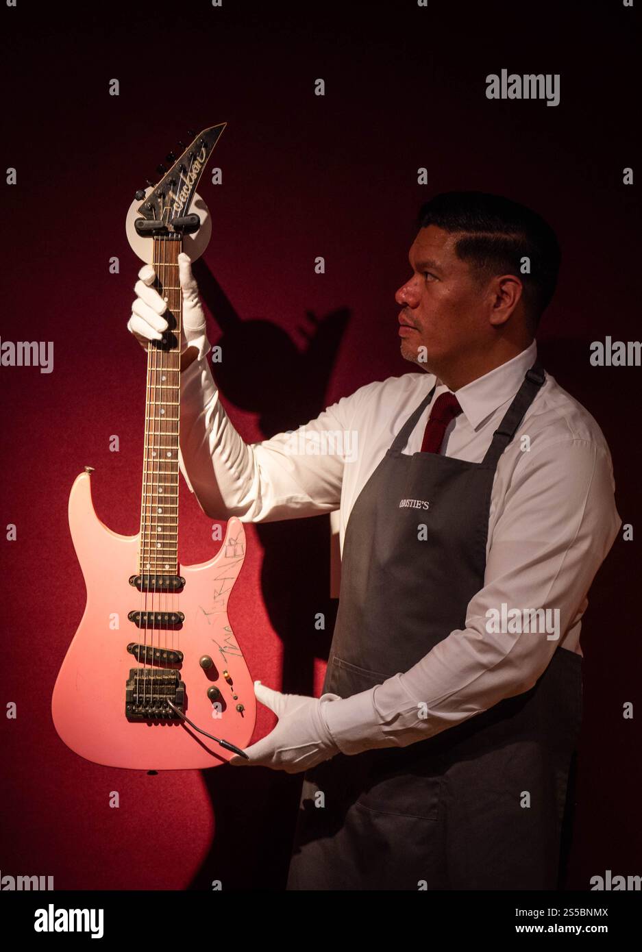 An art handler holds a 1983 Jackson guitar with an engraving made by ...