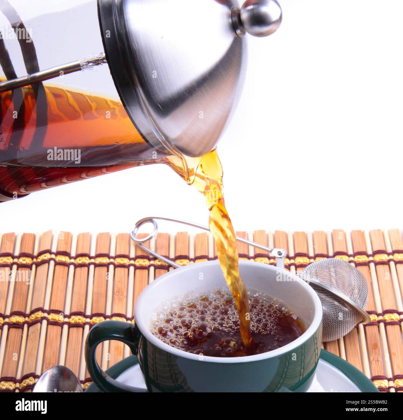 Pouring fresh tea kettle into green cup isolated on white background ...