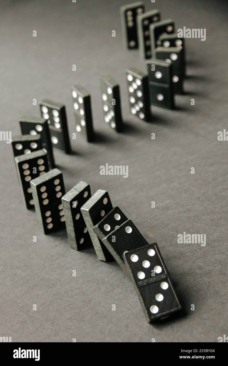 Black dominoes chain on a dark table background. Domino effect concept ...