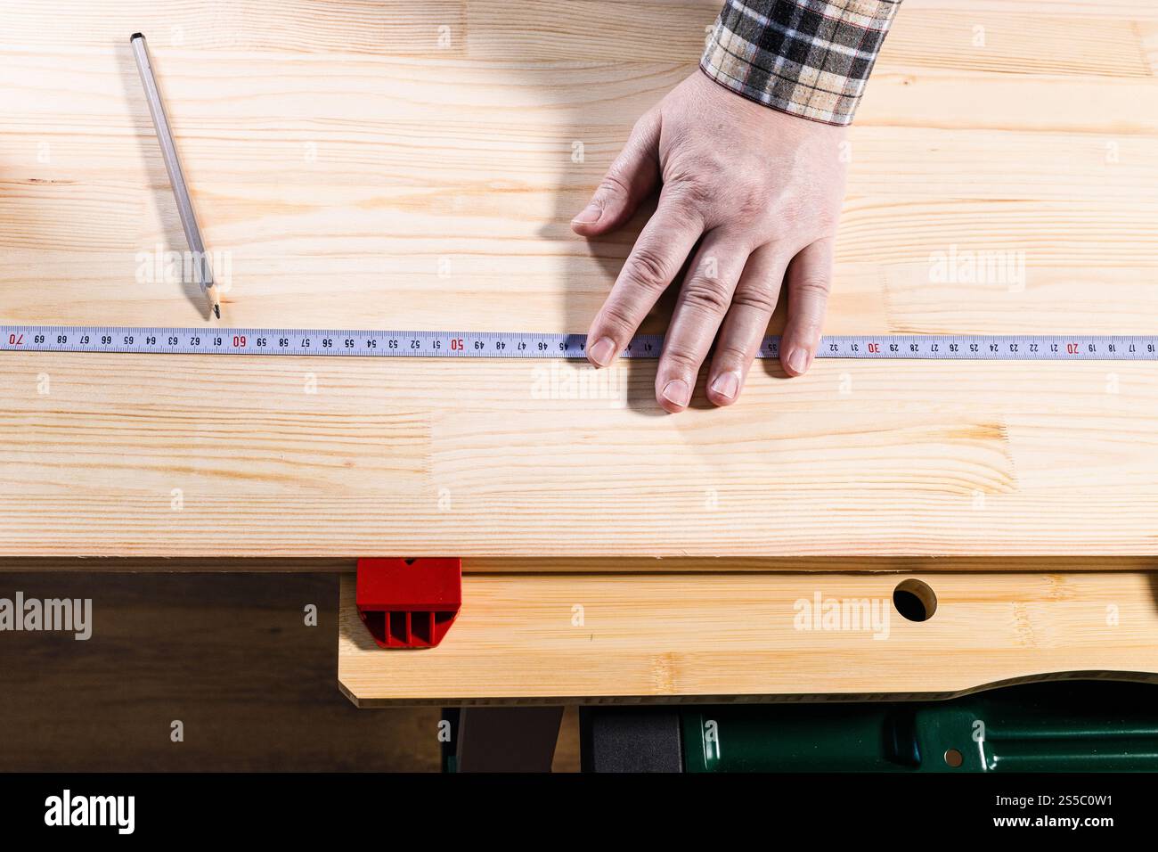top view of measuring tape on new wooden board on workbench at home ...