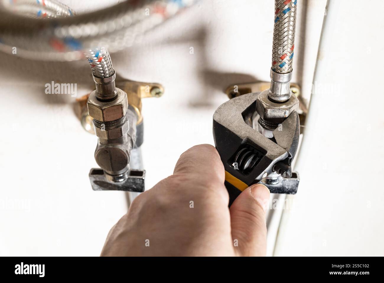 plumber hand fixes connection of tap by adjustable wrench closeup at ...