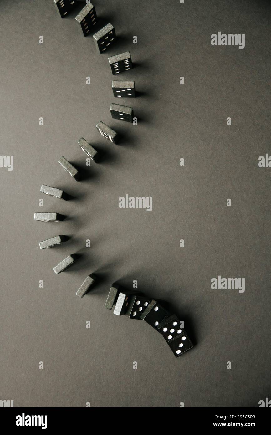 Black dominoes chain on a dark table background. Domino effect concept ...