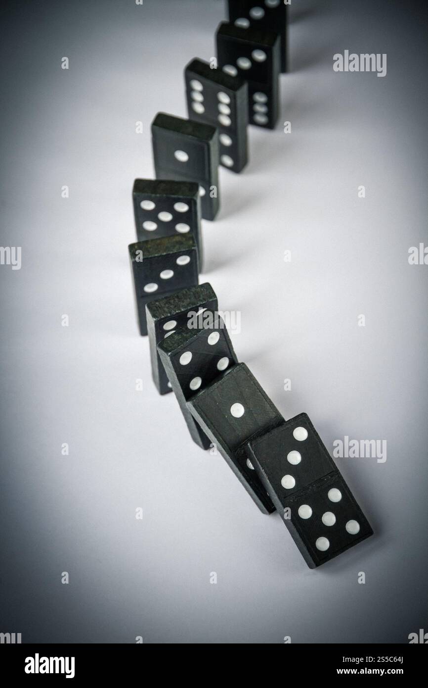 Black dominoes chain on a white table background. Domino effect concept ...