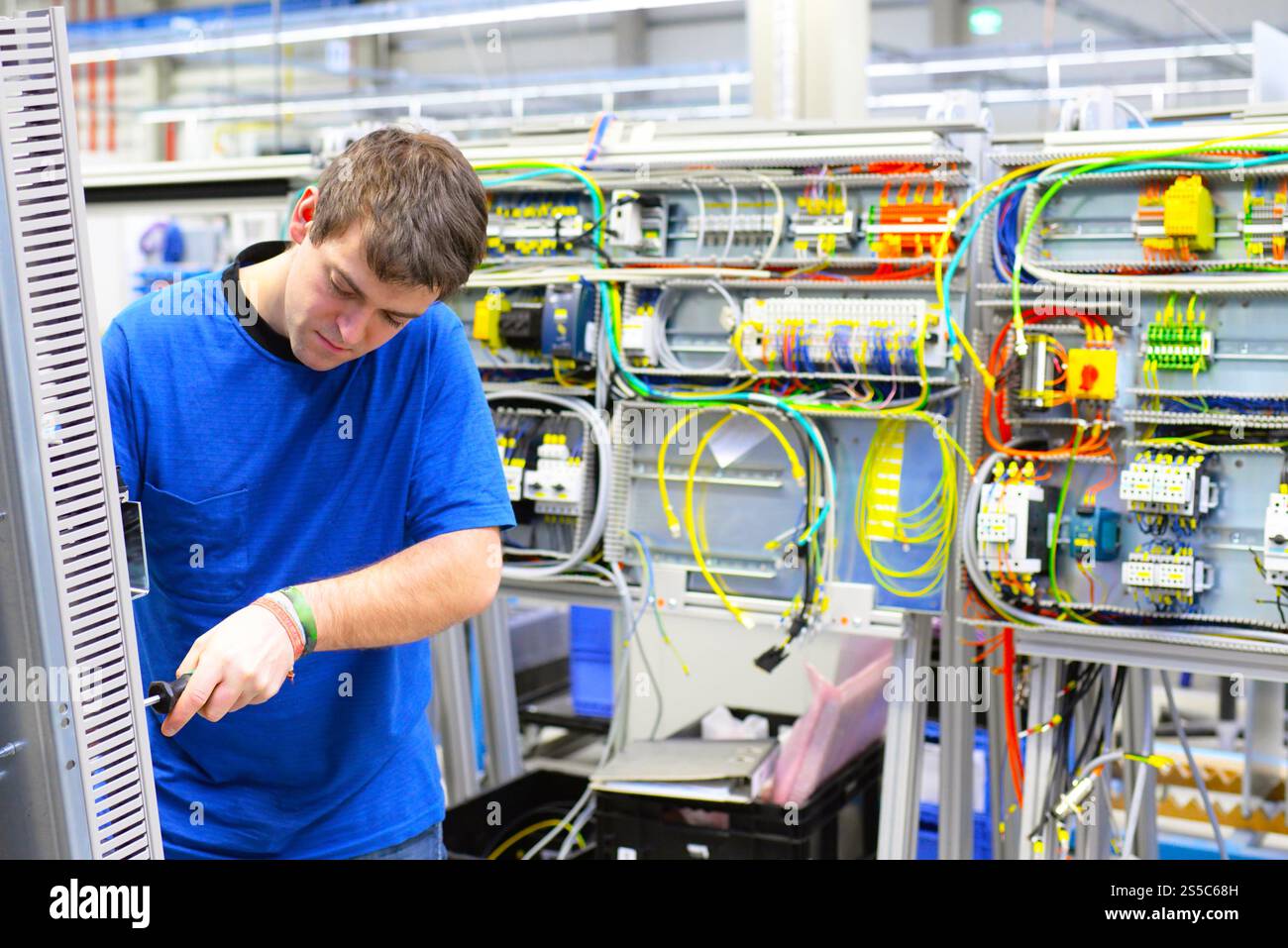young apprentice assembles components and cables in a factory in a ...