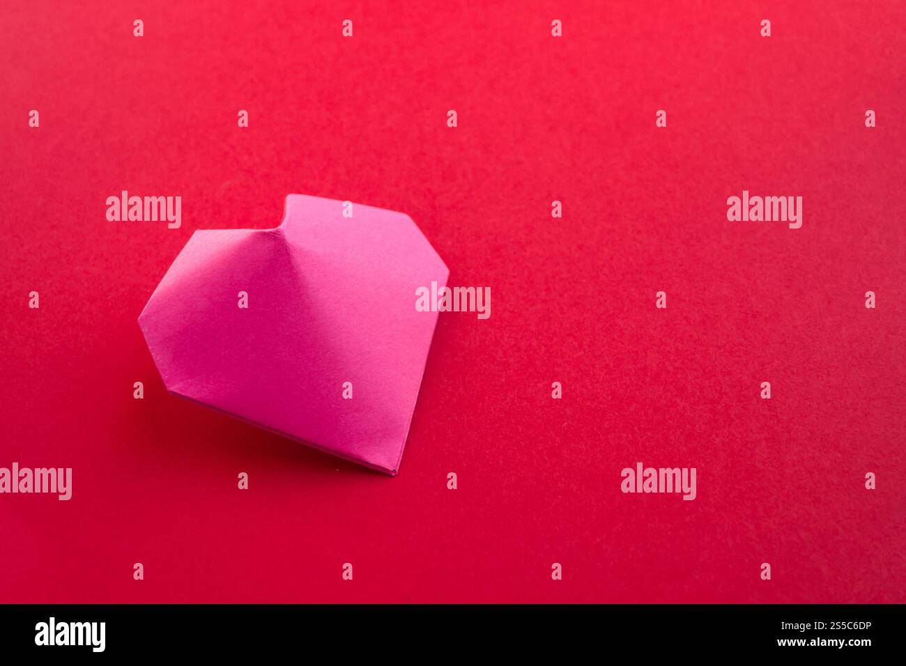 Pink paper heart origami isolated on a blank red background. Valentines ...