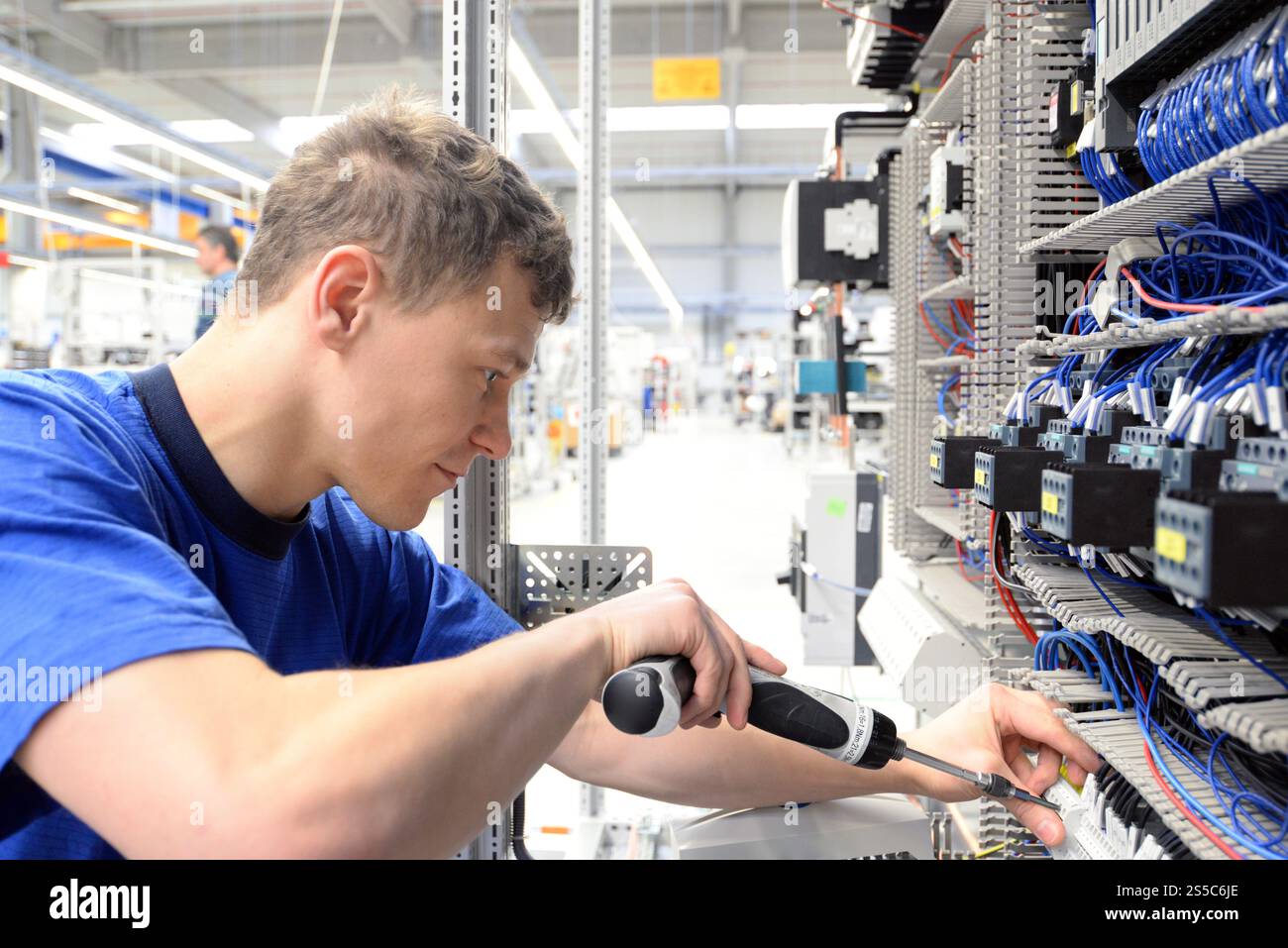young apprentice assembles components and cables in a factory in a ...