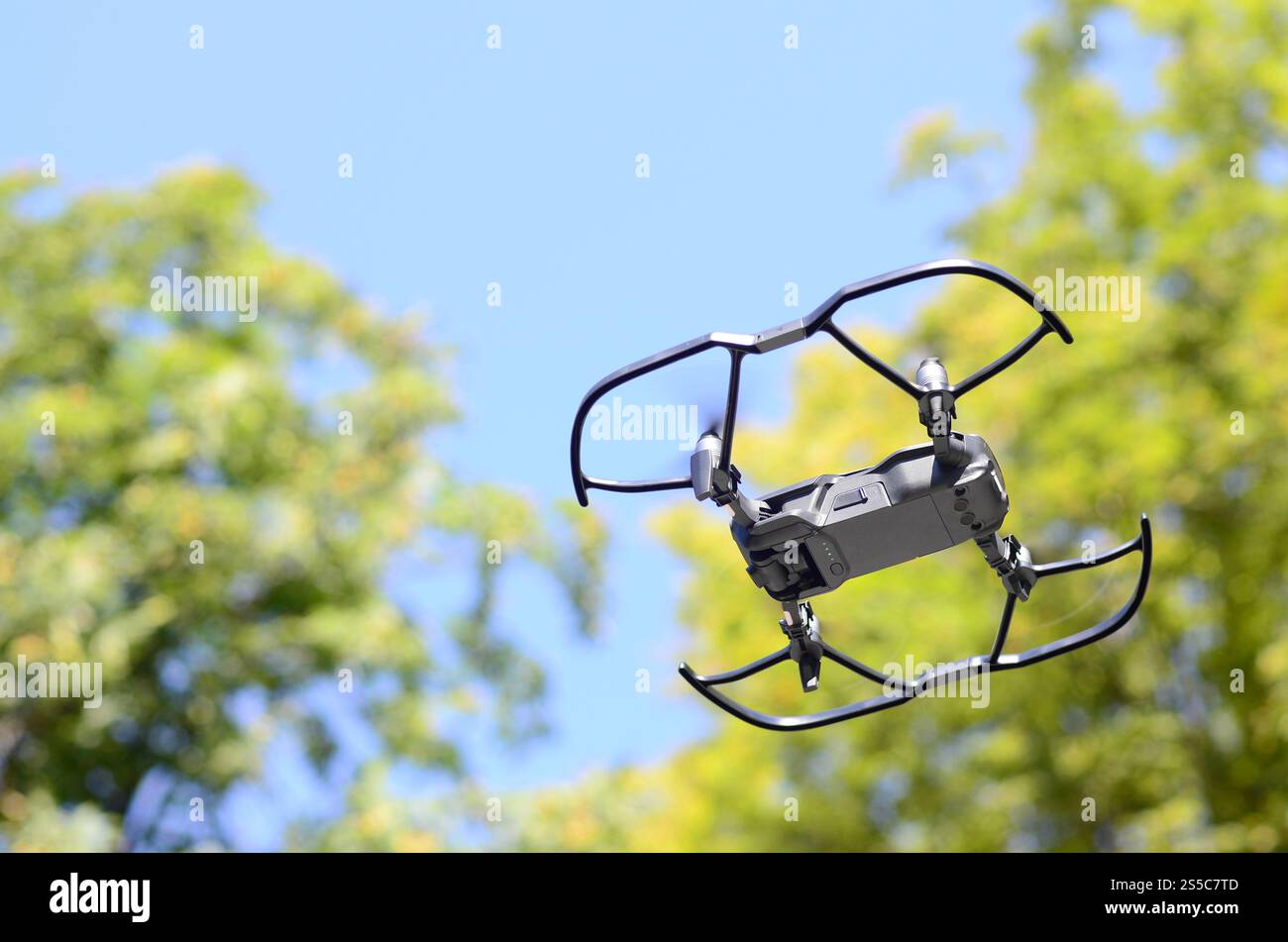 Small UAV drone copter with digital camera is flying near the green ...