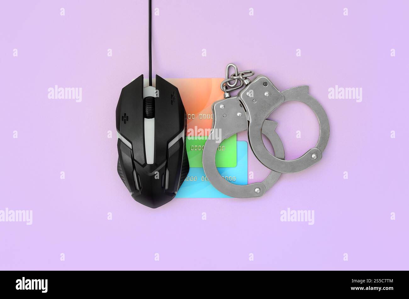 Computer mouse, credit cards and police handcuffs are on a pastel ...