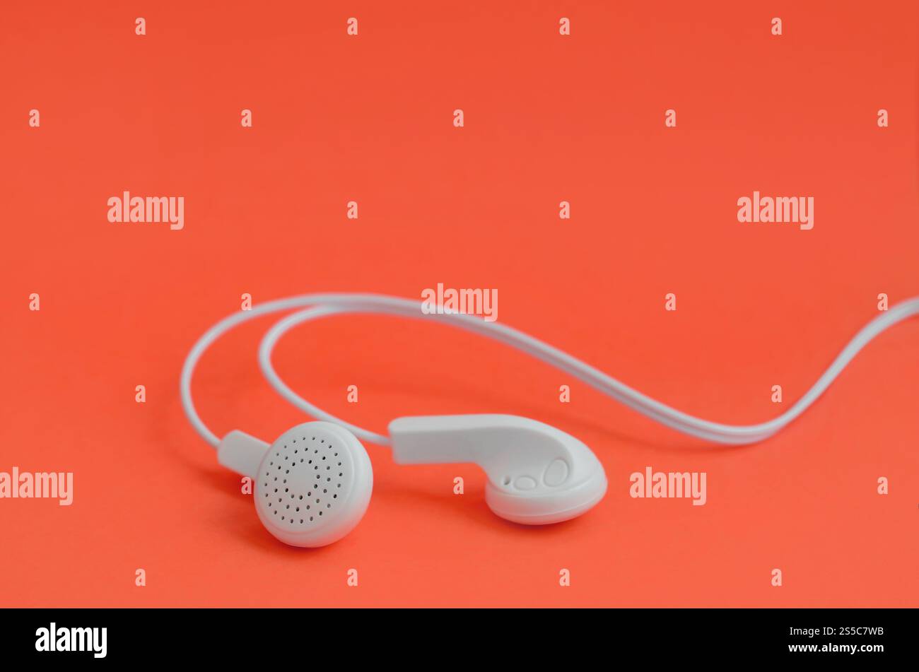 White modern headphones lie on a bright red background. A template for ...