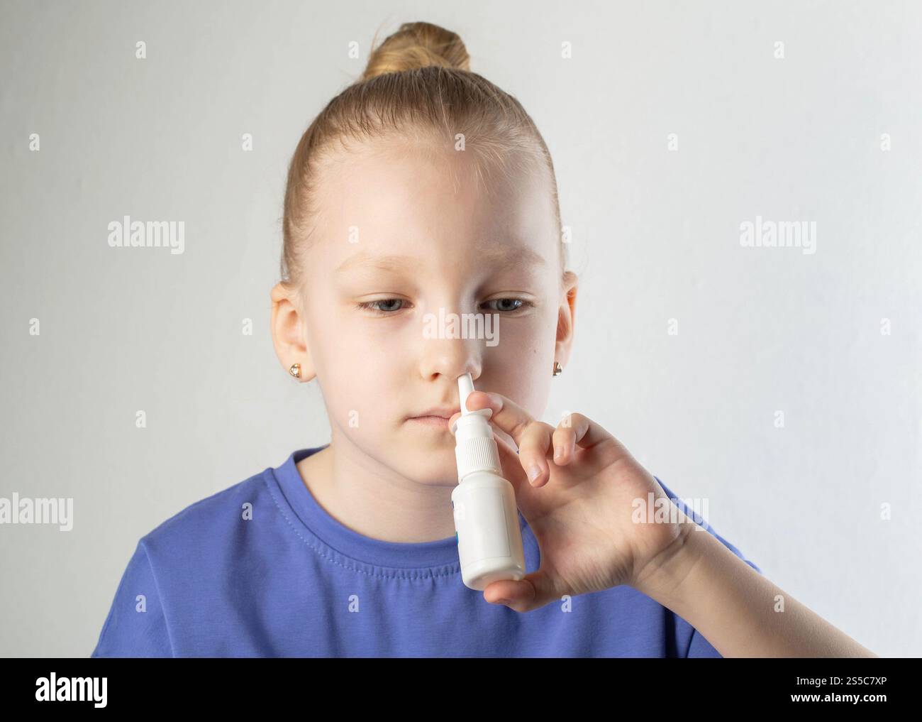 A girl sprays a spray into her nose to treat allergic rhinitis ...