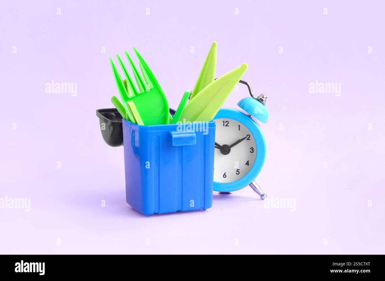 Alarm clock and plastic cutlery in trash bin on pink background. Time ...