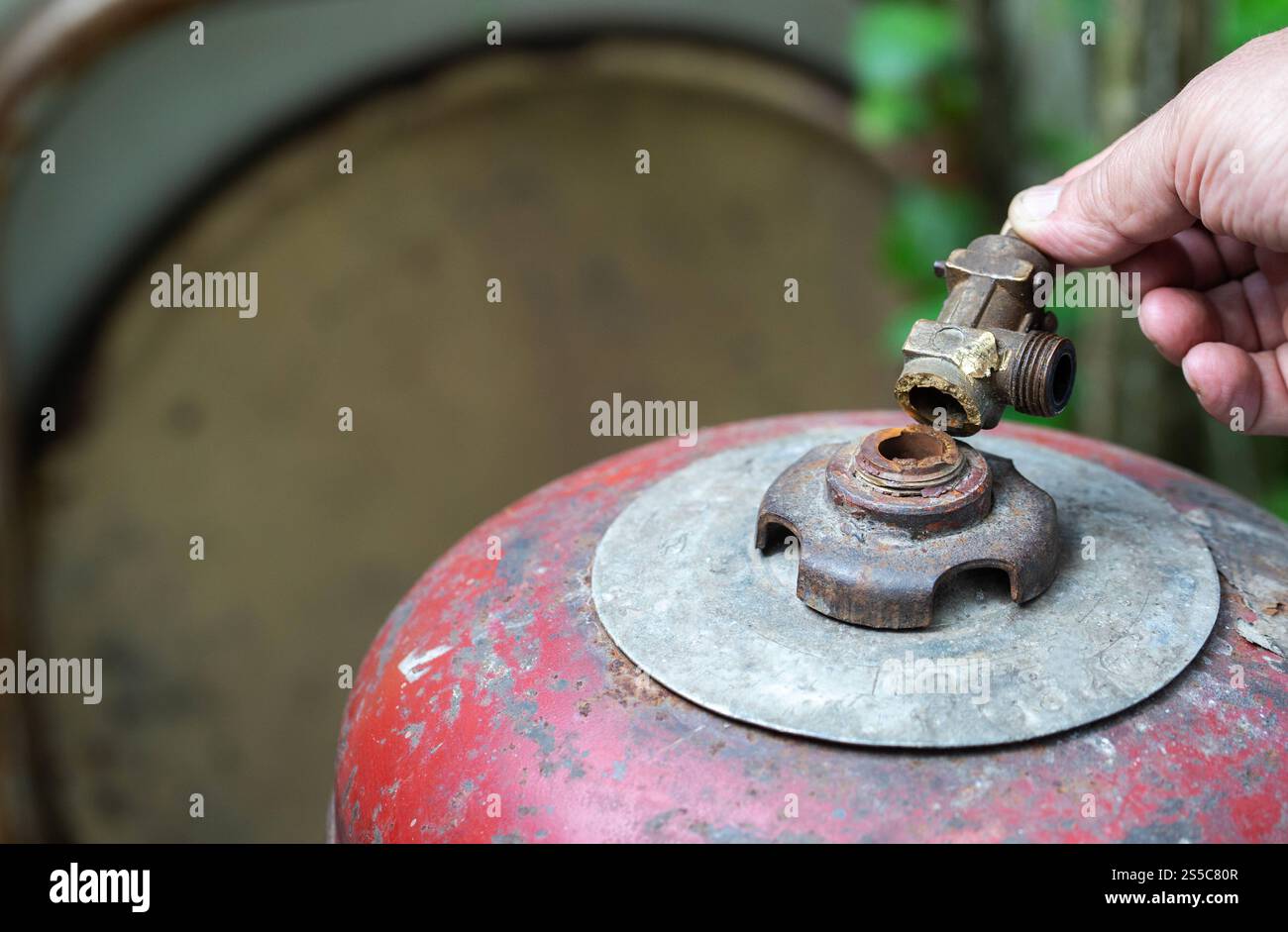 A broken valve of a gas cylinder in a hand against the background of a ...
